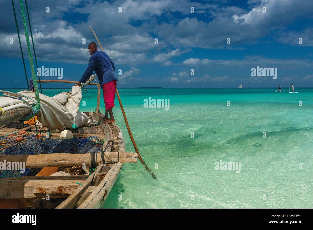 Tanzania, Zanzibar, Kendwa, fisherman on his boat pushing his boat with ...