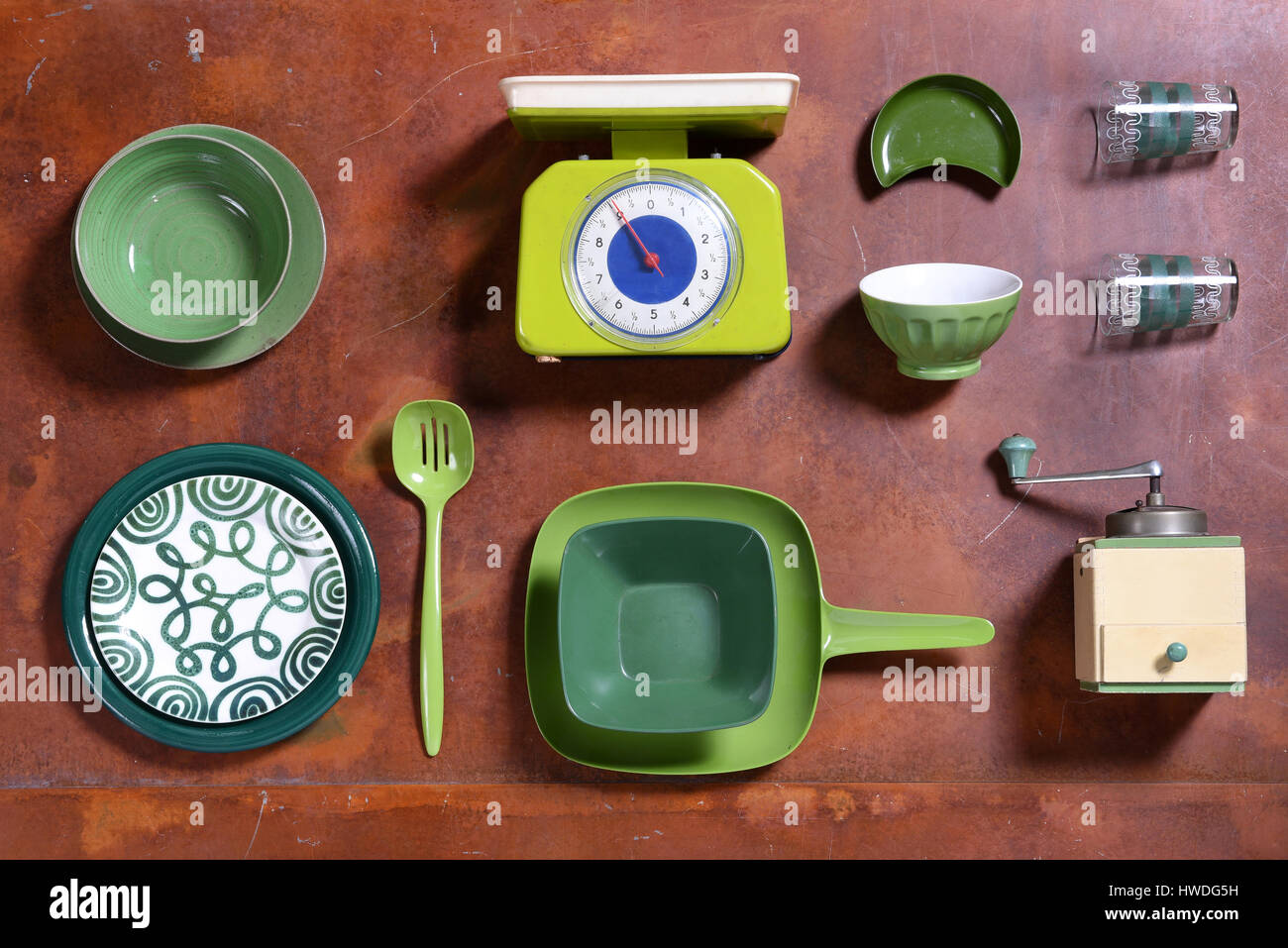 Assortment of green themed kitchen tools on a wooden table with a scale ...