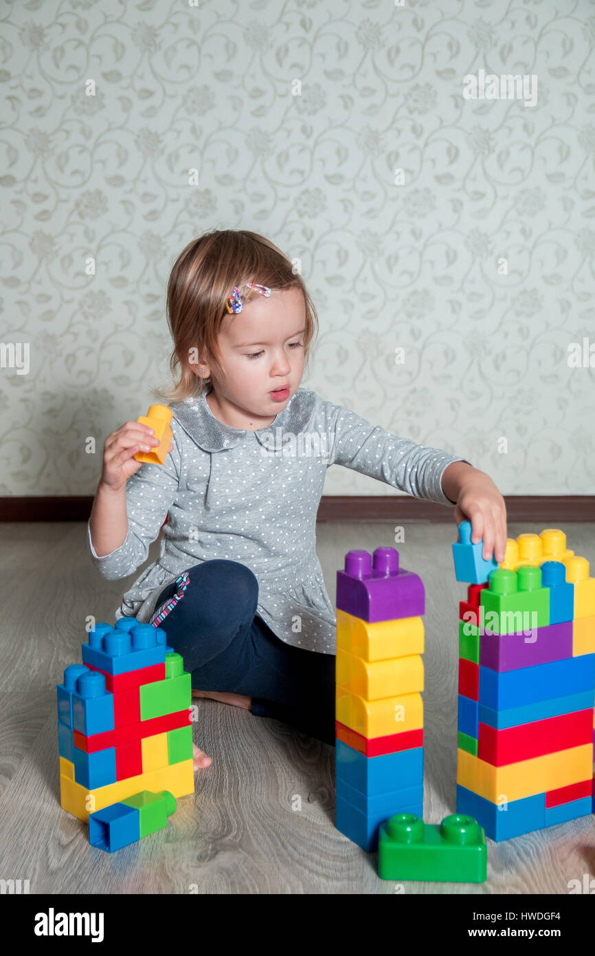 Child girl having fun and build of bright plastic construction blocks. Toddler playing on the ...