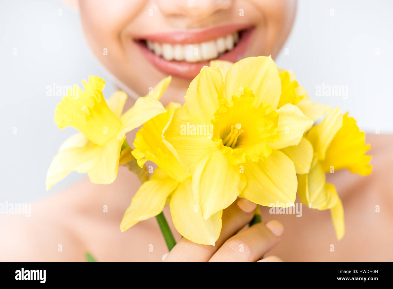 Lower part of female face and close up of yellow daffodils Stock Photo ...