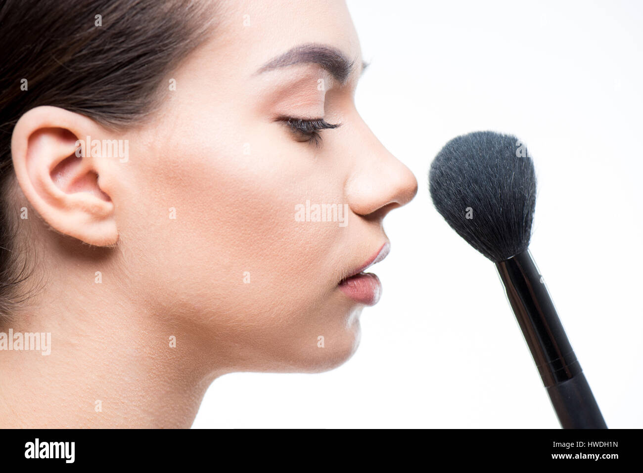 Side view of beautiful woman powder face with brush isolated on white ...