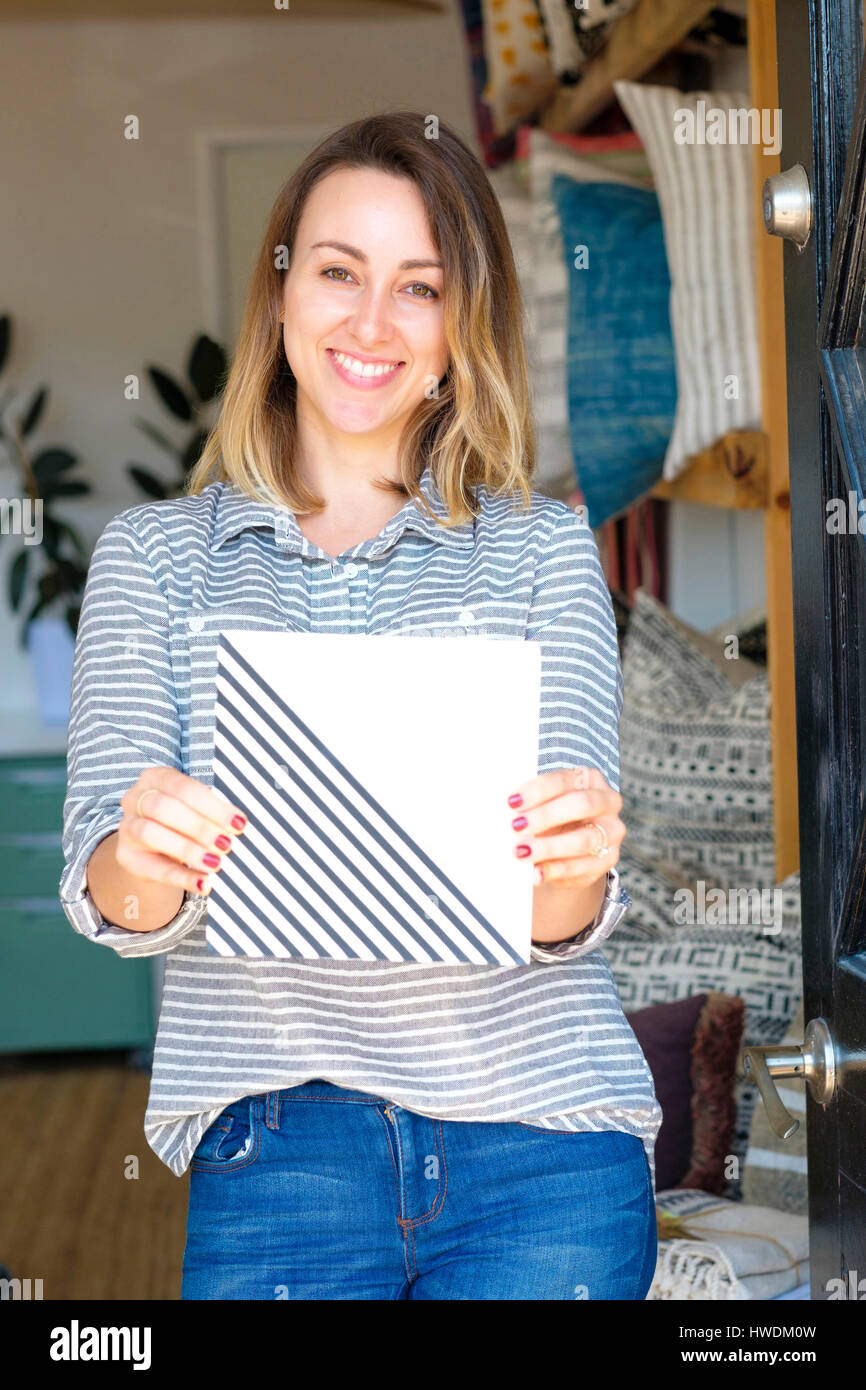 Portrait of female interior designer holding ceramic tile in retail ...