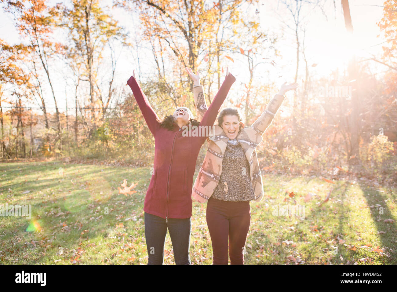 Two female friends throwing autumn leaves Stock Photo - Alamy