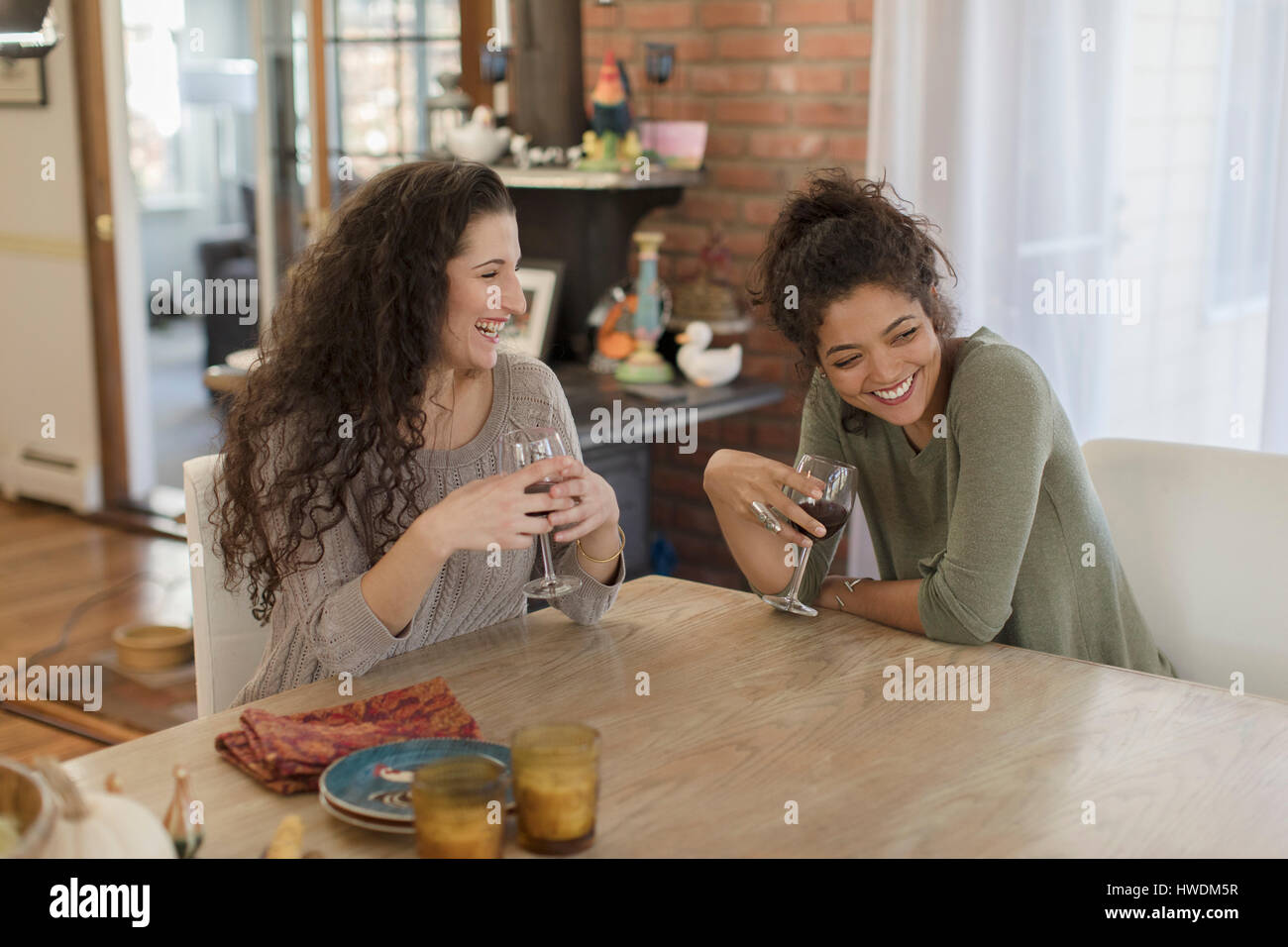 Two young women friends laughing at kitchen table Stock Photo - Alamy