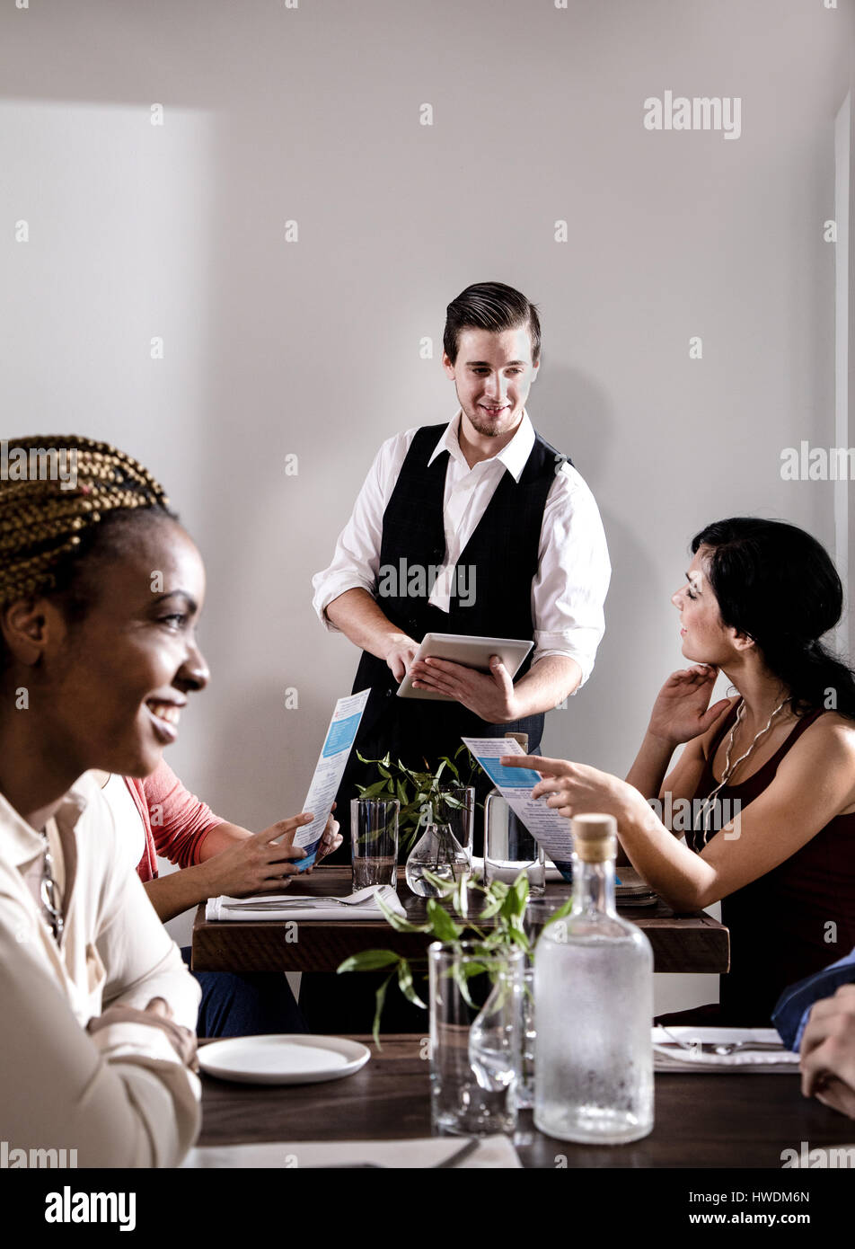 Waiter serving diners in restaurant, waiter using digital tablet Stock ...