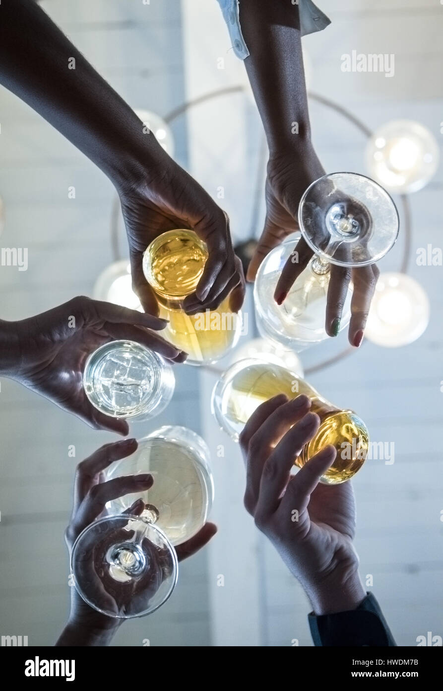 Group of friends making a toast, upward view of hands holding glasses ...