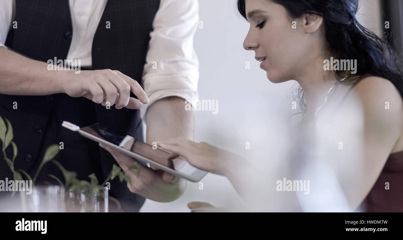 Waiter serving diner in restaurant, diner using digital tablet to pay ...