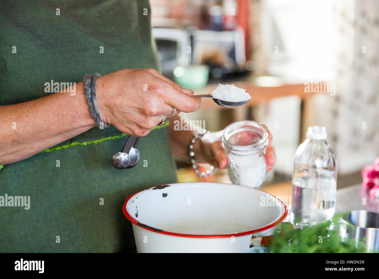 Hand of woman adding sea salt to bowl in kitchen Stock Photo - Alamy