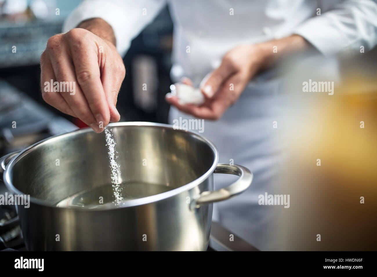 Chef putting salt in pan of water on stove, close-up Stock Photo - Alamy