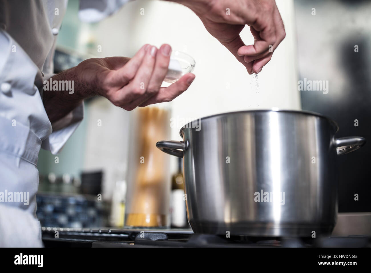 Chef putting salt in pan of water on stove, close-up Stock Photo - Alamy