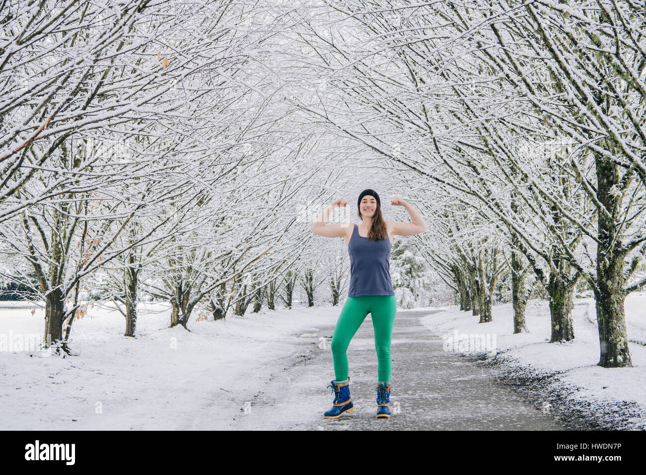 Portrait of woman flexing muscles, in snow covered rural landscape ...