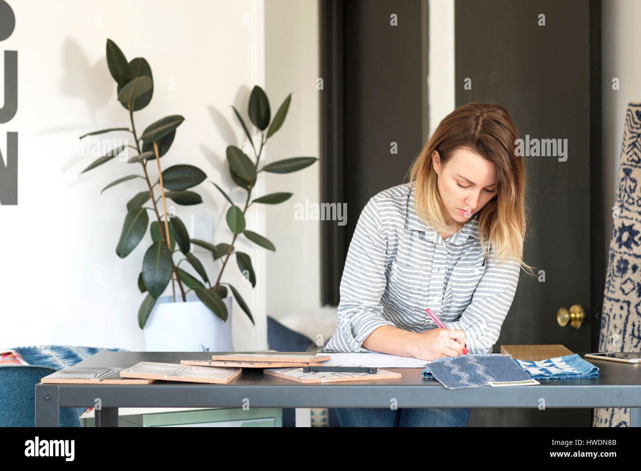 Female interior designer drawing designs at desk in retail studio Stock ...