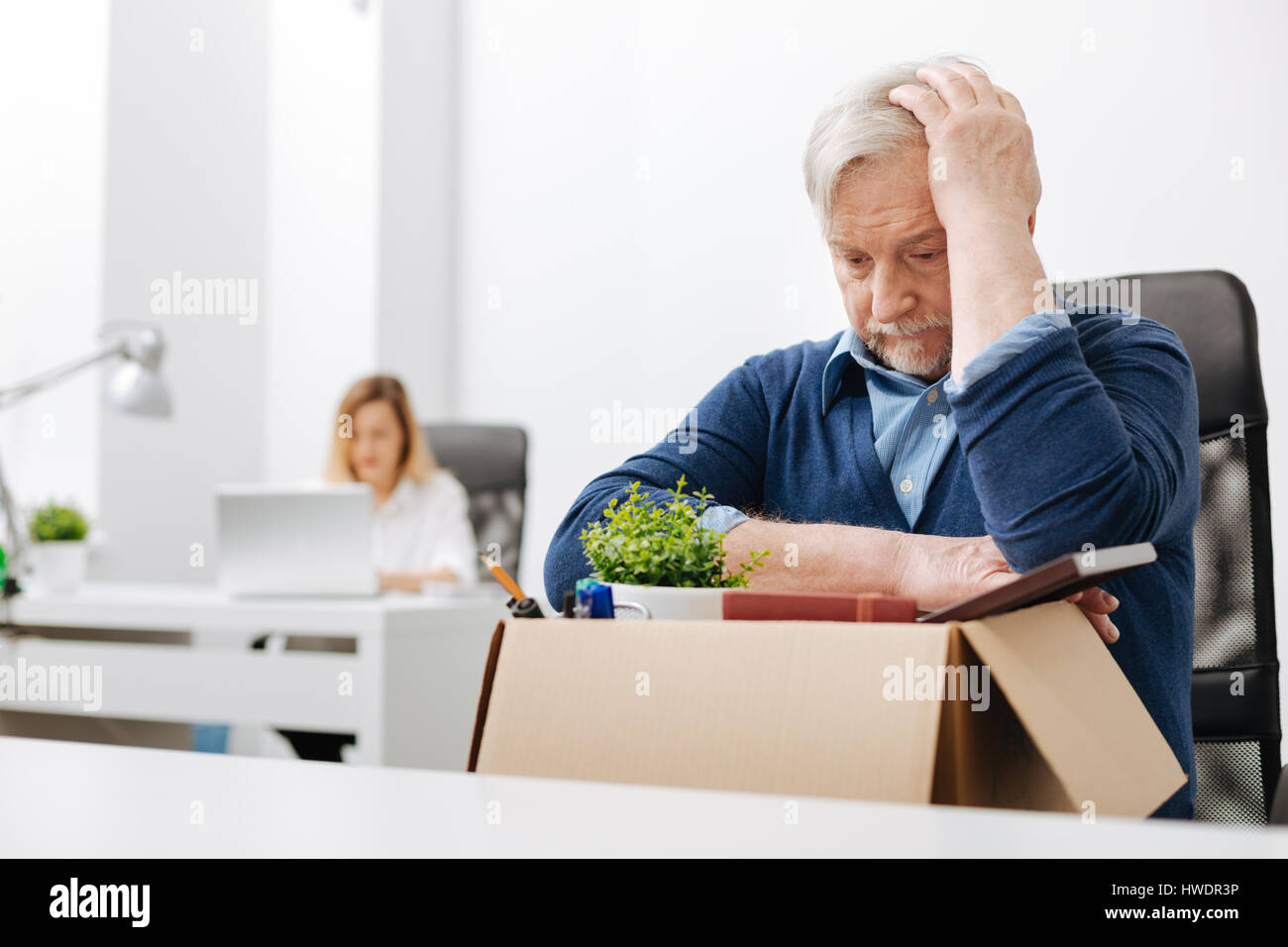 Upset office worker gathering belongings into the box Stock Photo - Alamy