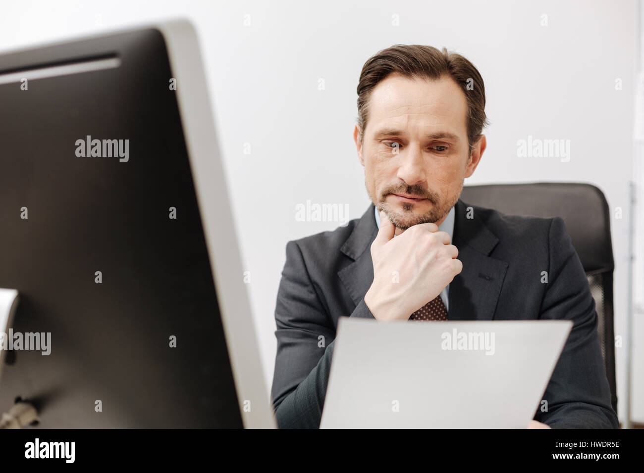 Thoughtful office manager reading documents in the office Stock Photo ...