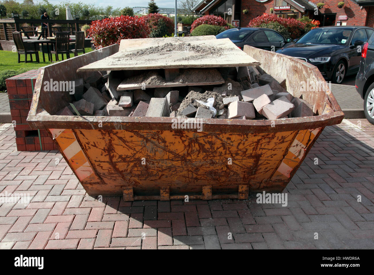 A battered skip with bricks from a demolition, plasterboard and mortar ...