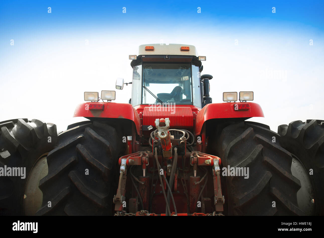 Modern red tractor on a blue sky background close-up Stock Photo - Alamy