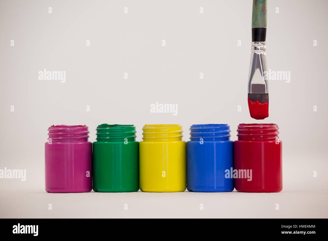 Watercolor paints and paint brush with red paint dipped into red color ...