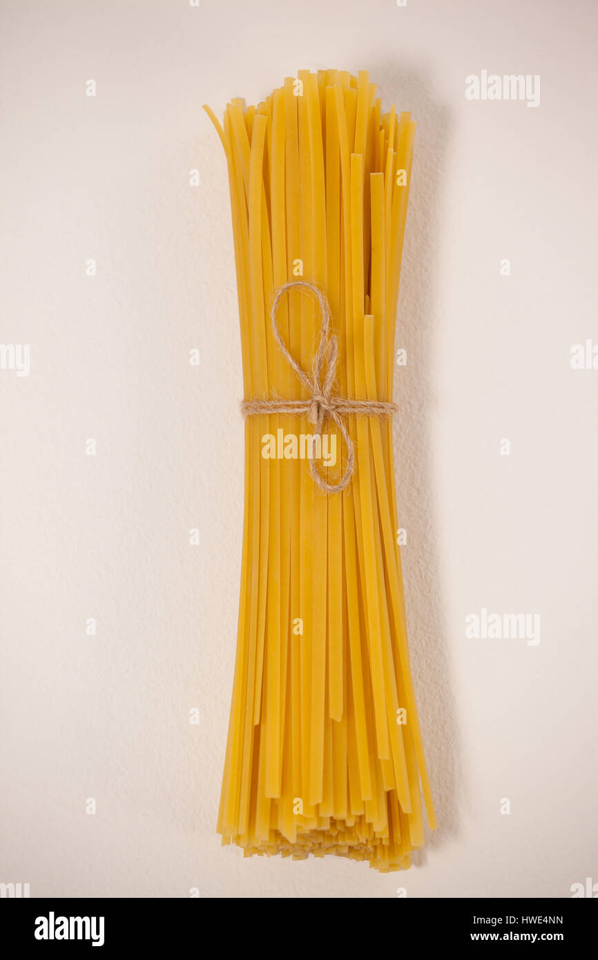 Bundle of raw spaghetti tied with rope on white background Stock Photo ...