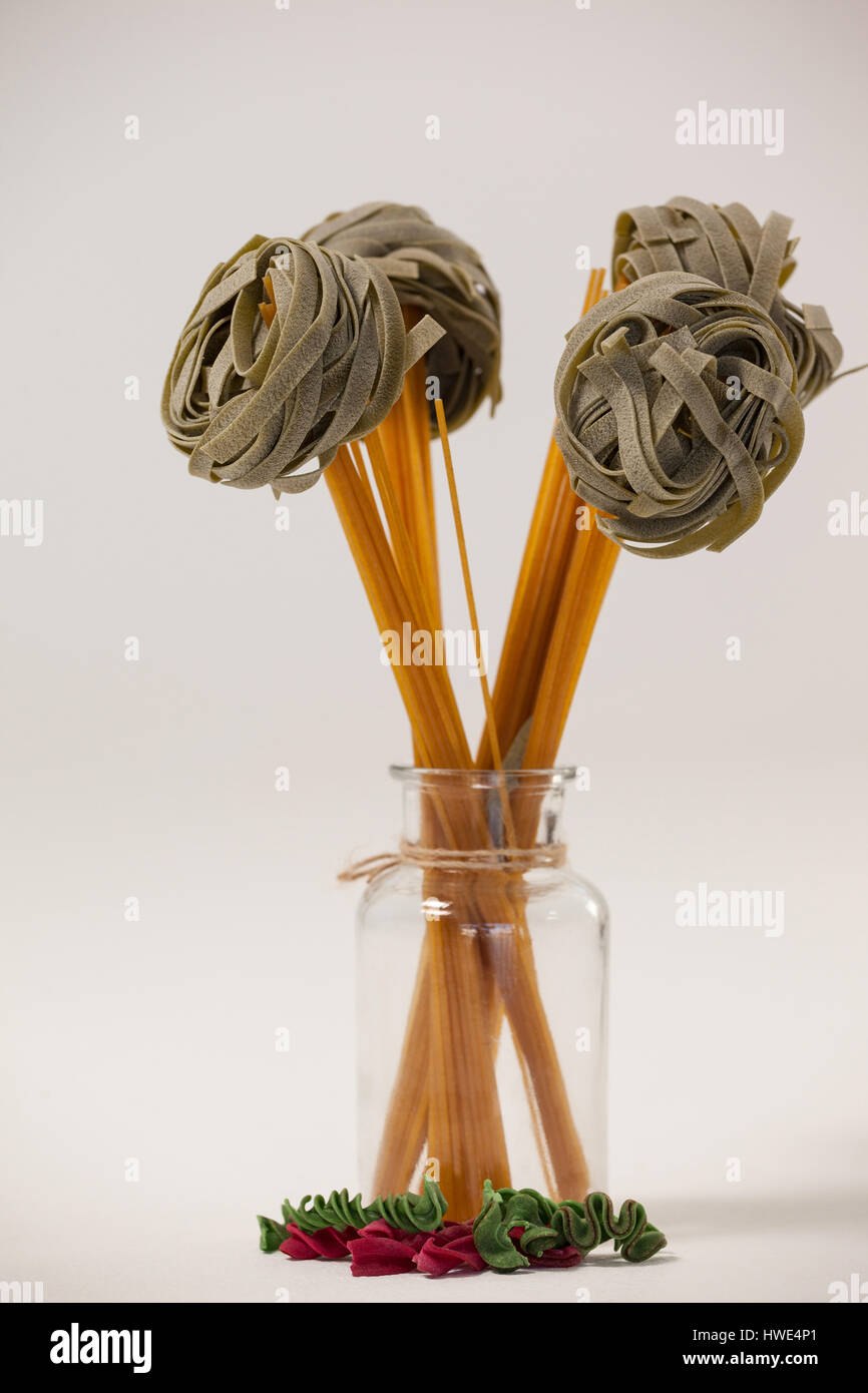Spaghetti and fettuccine pasta arranged in shape of plant on white ...