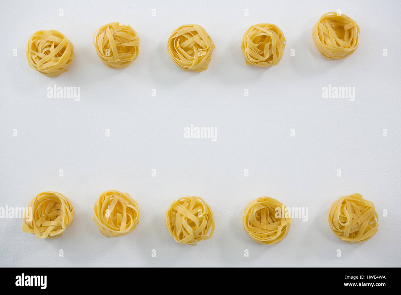 Fettuccine pasta arranged in a row on white background Stock Photo - Alamy