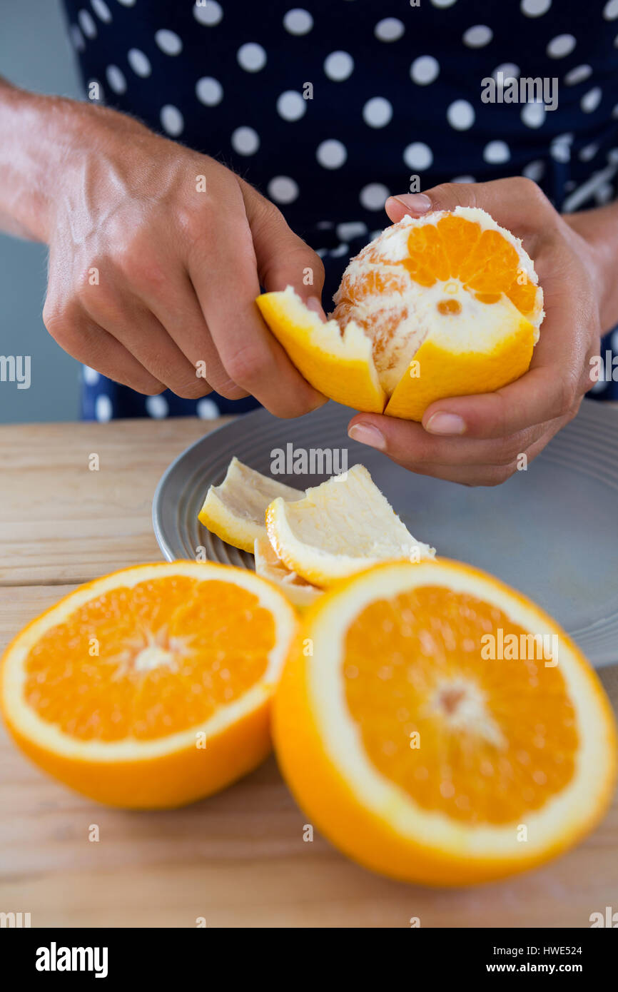 Mid-section of woman peeling orange Stock Photo - Alamy