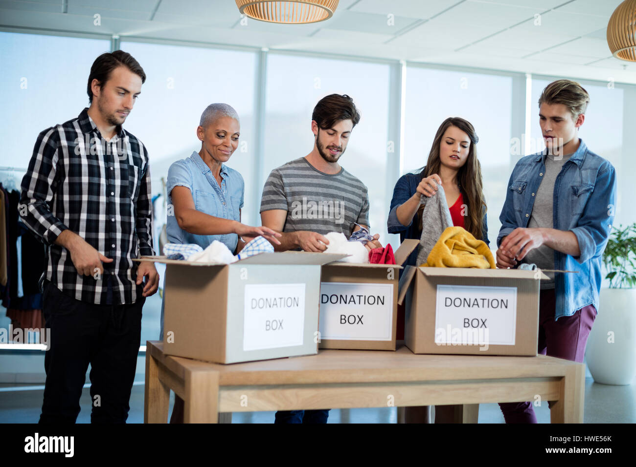 Creative business team sorting clothes in donation box in office Stock ...