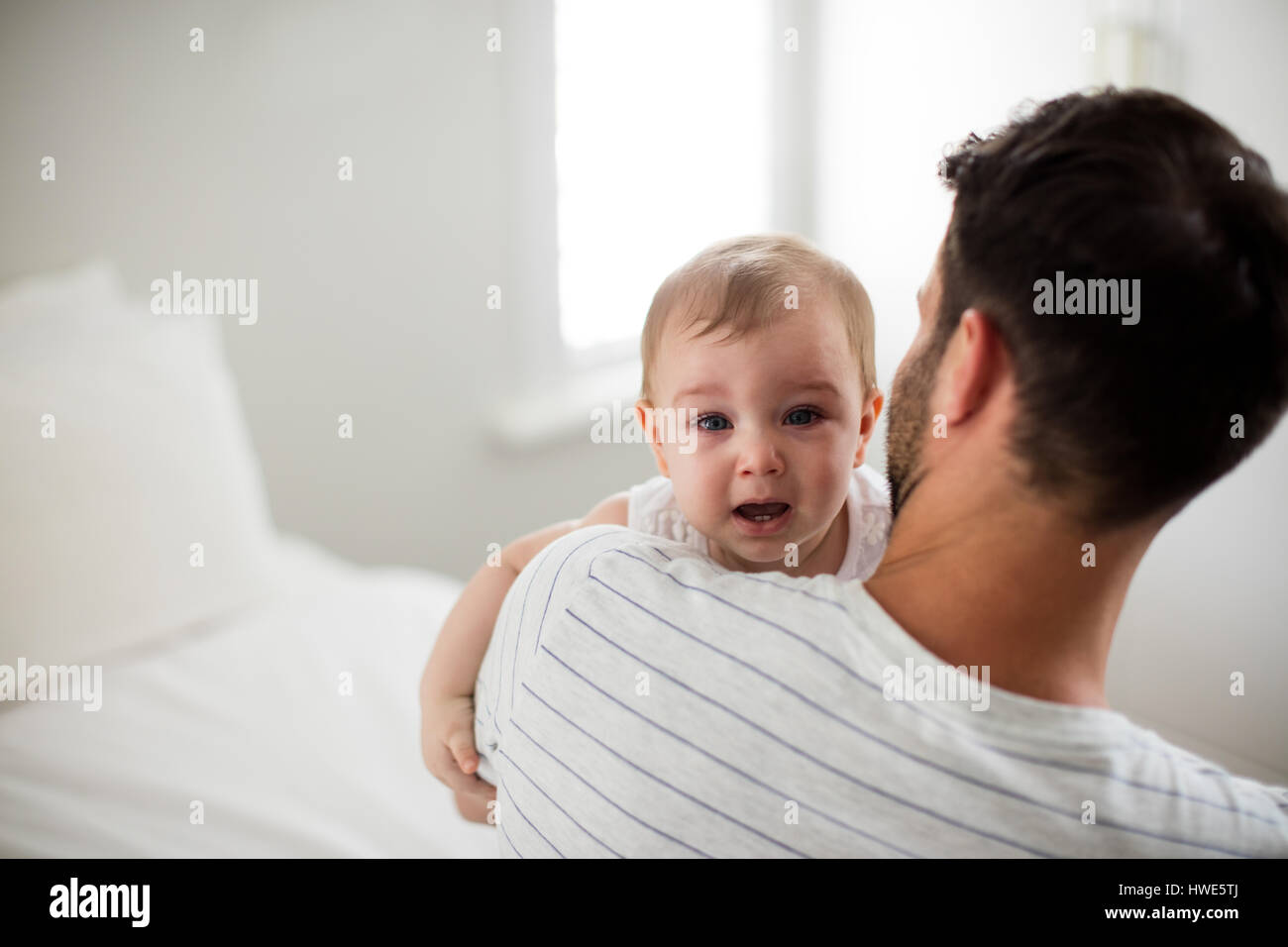 Father holding his crying baby girl at home Stock Photo - Alamy