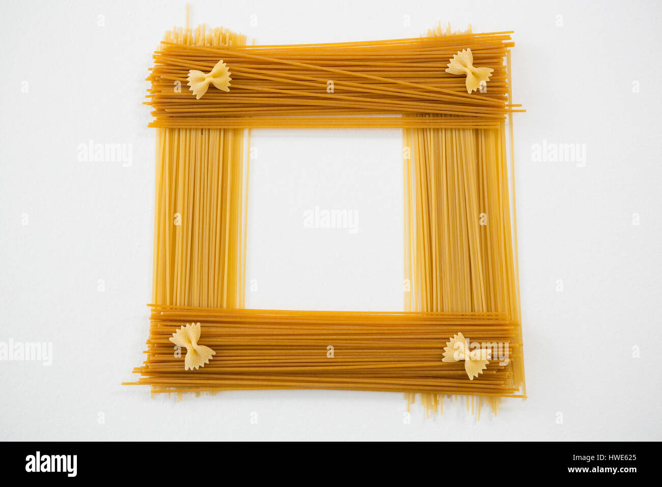 Farfalle and spaghetti pasta forming frame on white background Stock ...