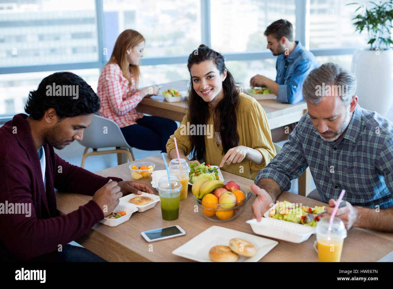 Smiling creative business team having meal in office Stock Photo - Alamy