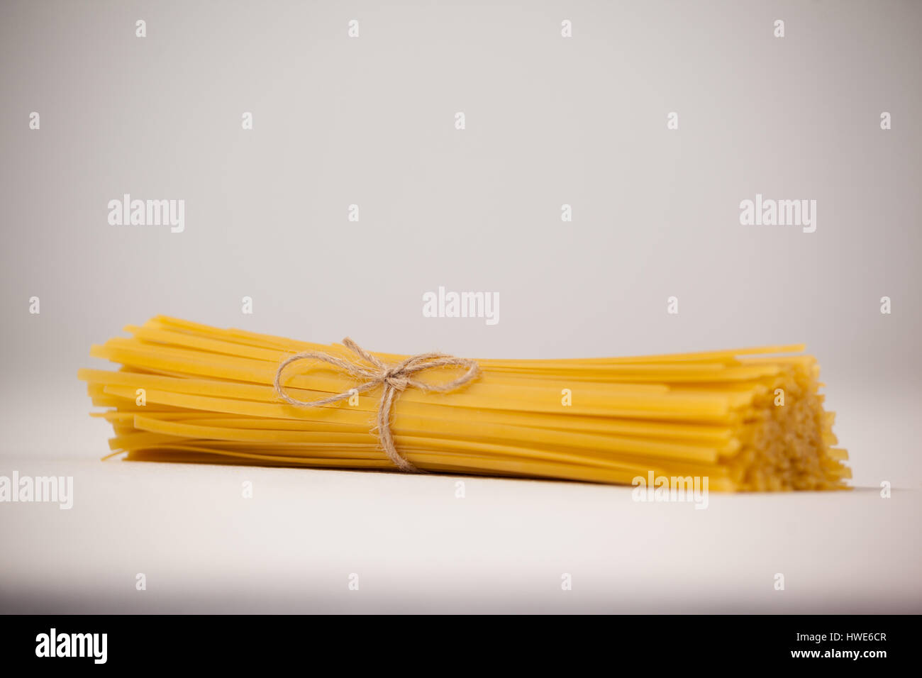Bundle of raw spaghetti tied with rope on white background Stock Photo ...