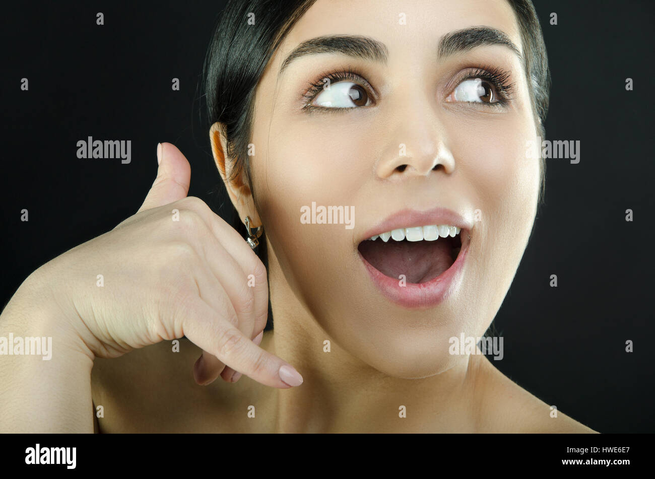 Portrait of a brown-eyed woman who making call me gesture sign with ...
