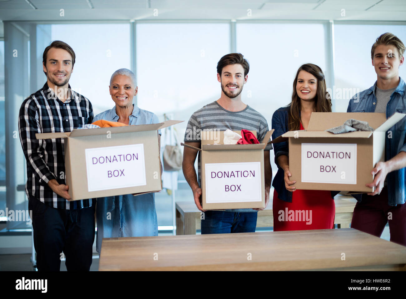 Portrait of creative business team holding donation box in office Stock ...
