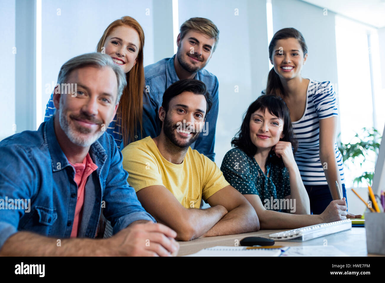 Portrait of smiling creative business team working together at desk in ...