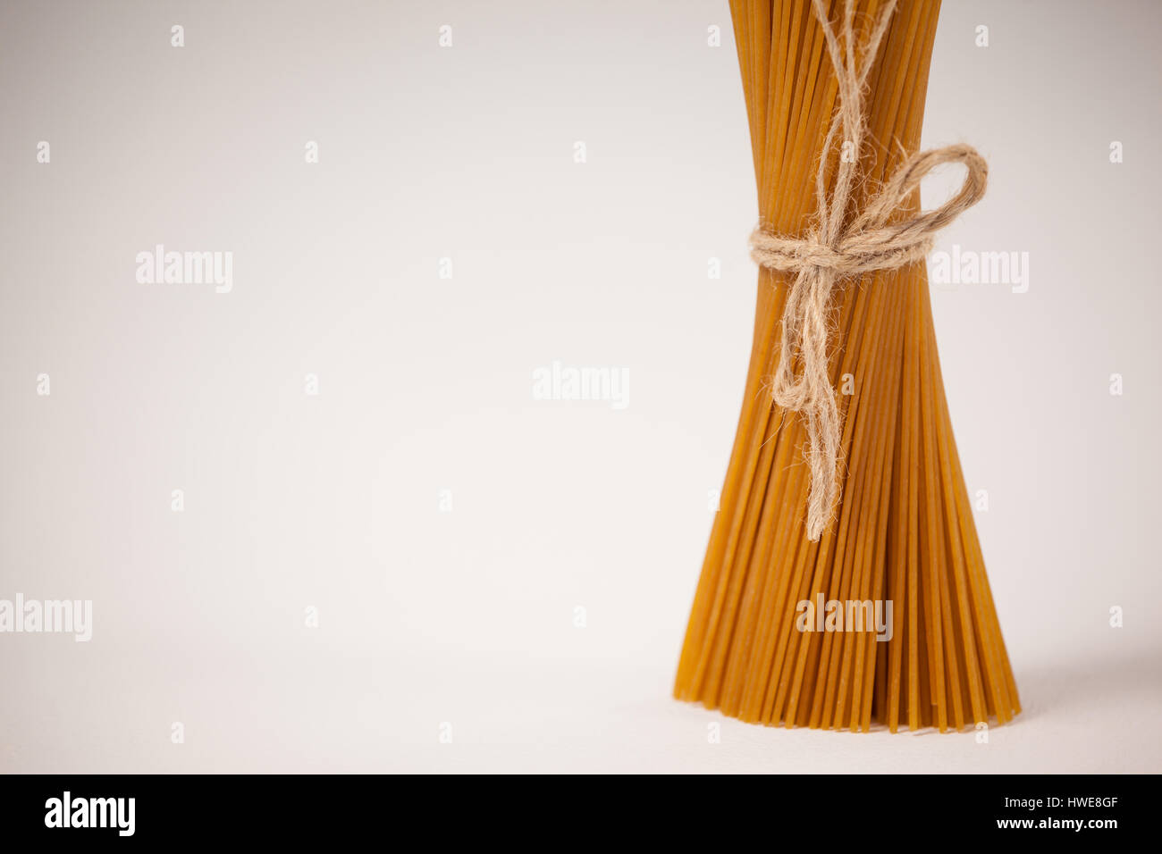 Bundle of raw spaghetti tied with rope on white background Stock Photo ...