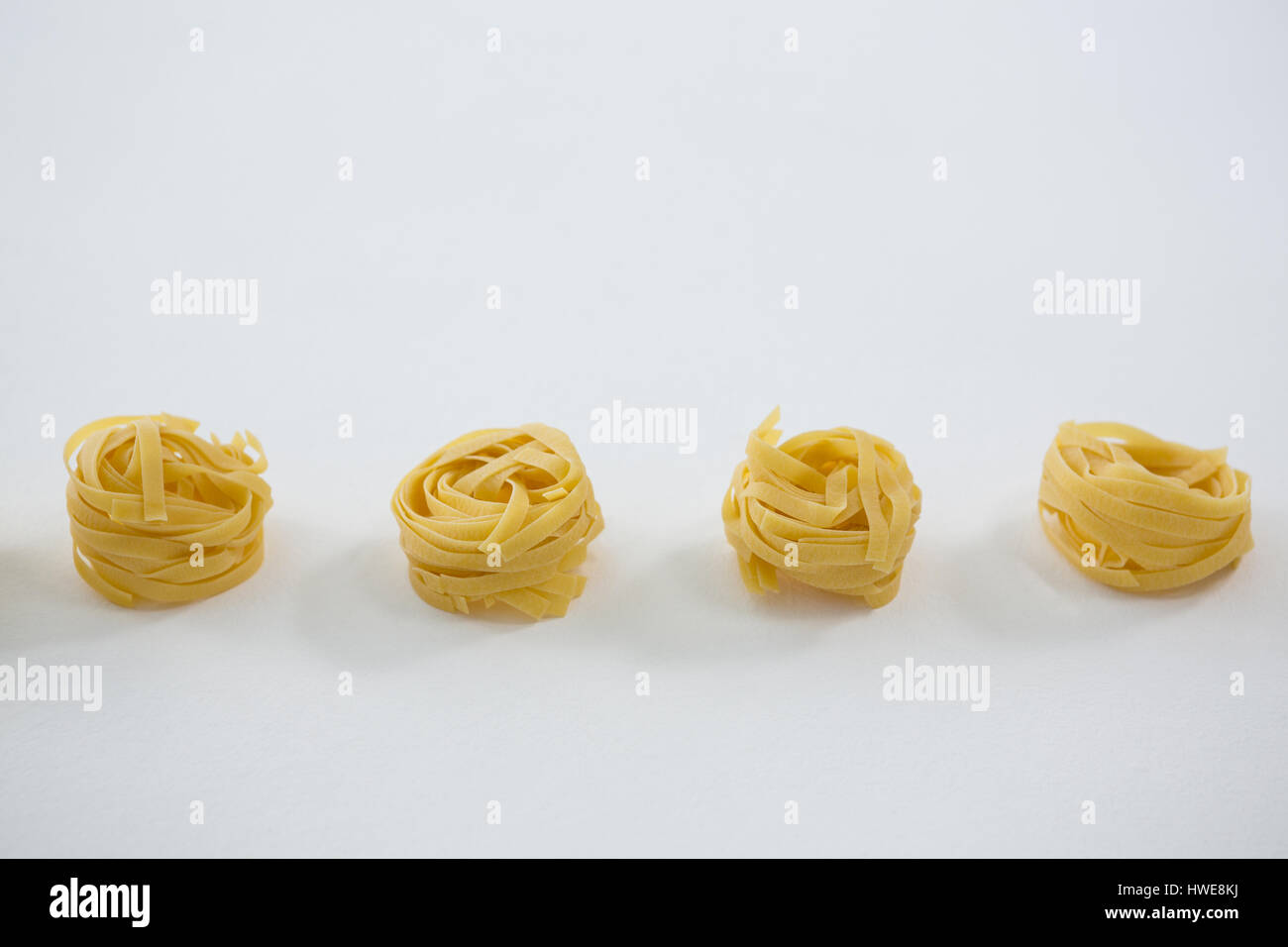 Fettuccine pasta arranged in a row on white background Stock Photo - Alamy
