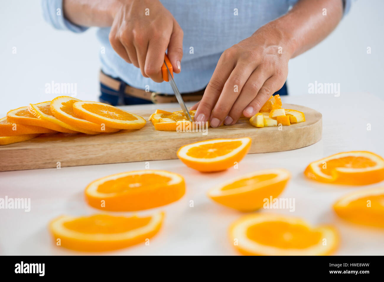 Mid-section of woman cutting fruits on chopping board against white ...