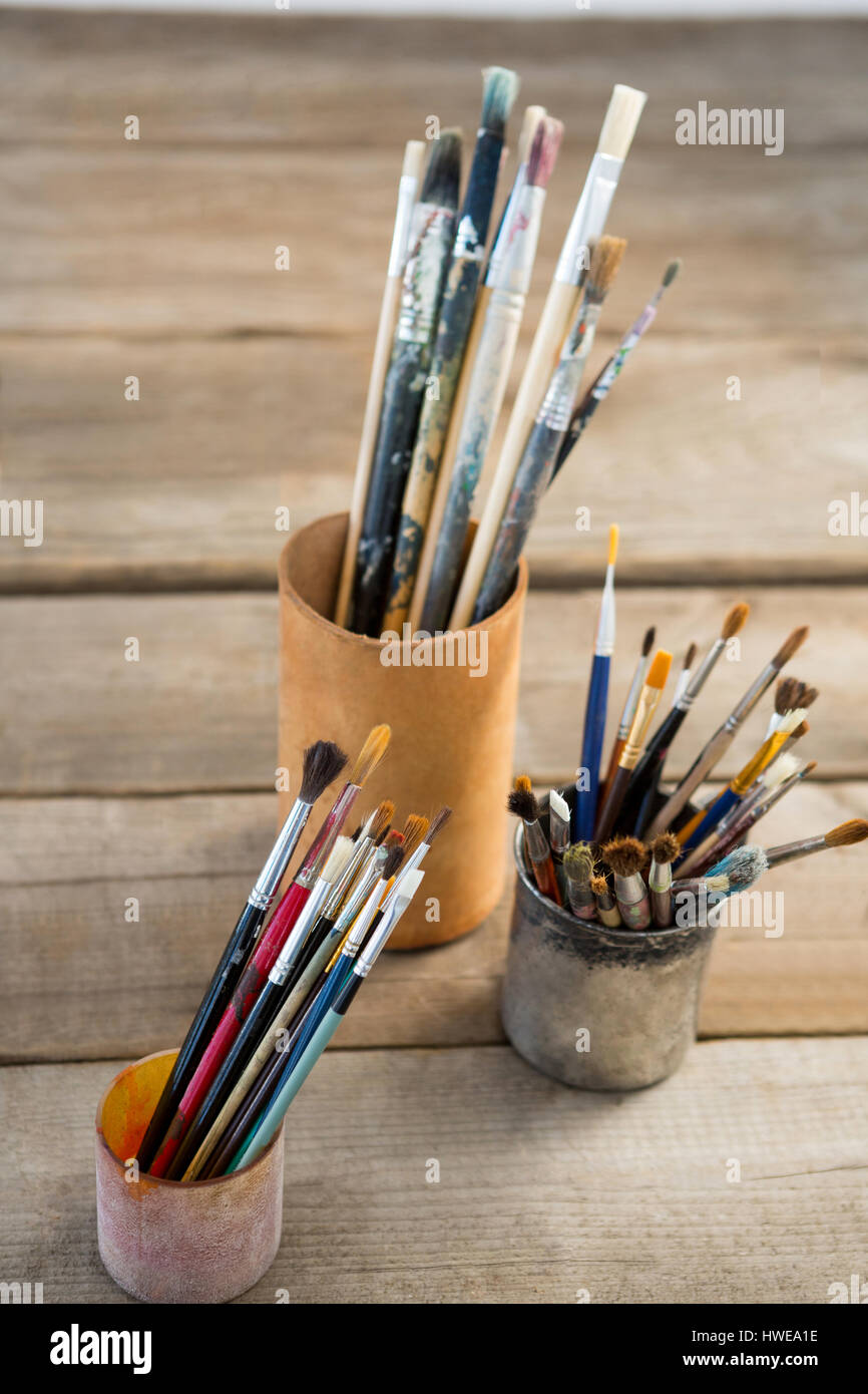 Various paintbrush in container on wooden surface Stock Photo - Alamy
