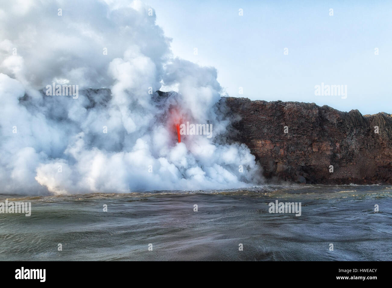 Red hot lava flows into Pacific Ocean from tube high on the cliffs on ...