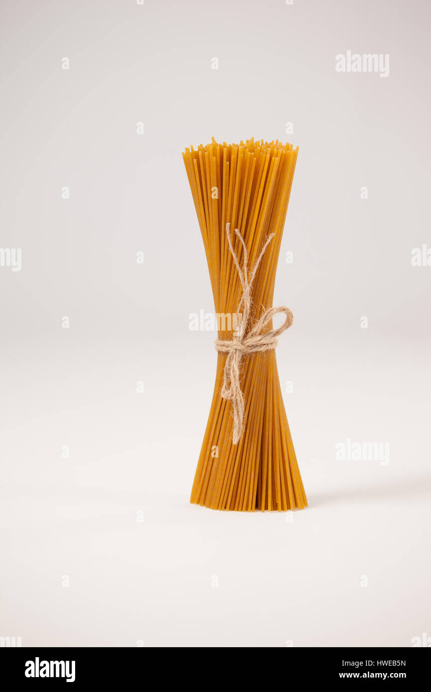 Bundle of raw spaghetti tied with rope on white background Stock Photo ...