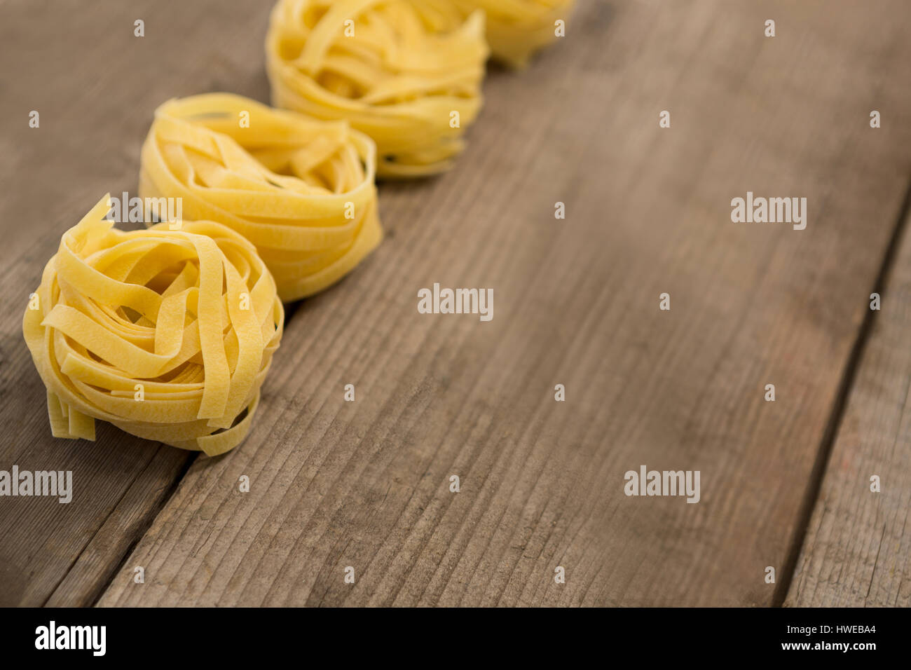 Fettuccine pasta arranged in a row on wooden background Stock Photo - Alamy