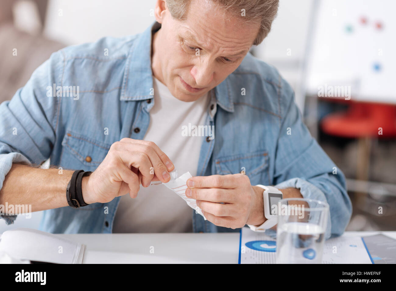 Concentrated man opening packet with medicine Stock Photo - Alamy