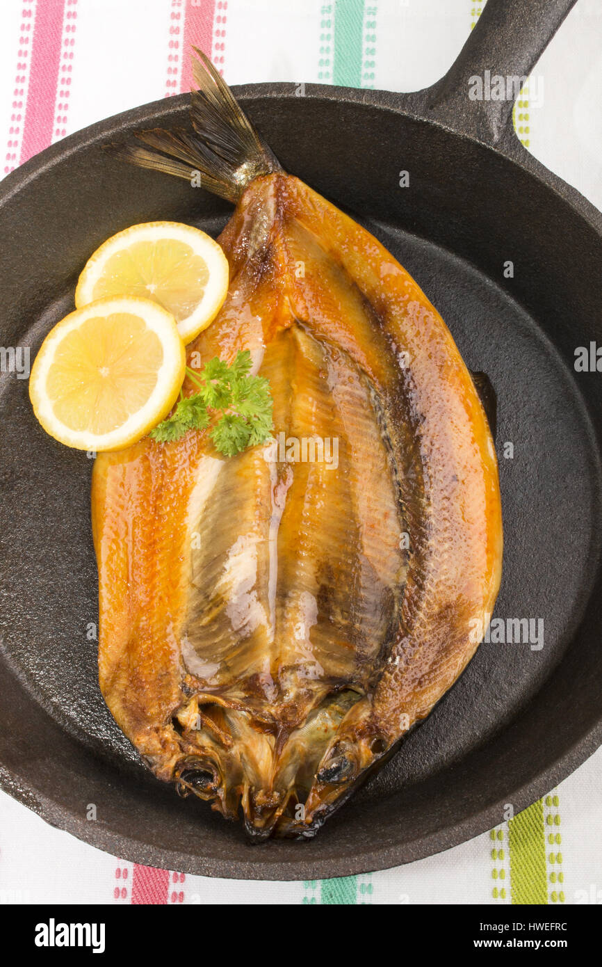 warm smoked kipper with lemon and parsley in a cast iron pan Stock ...