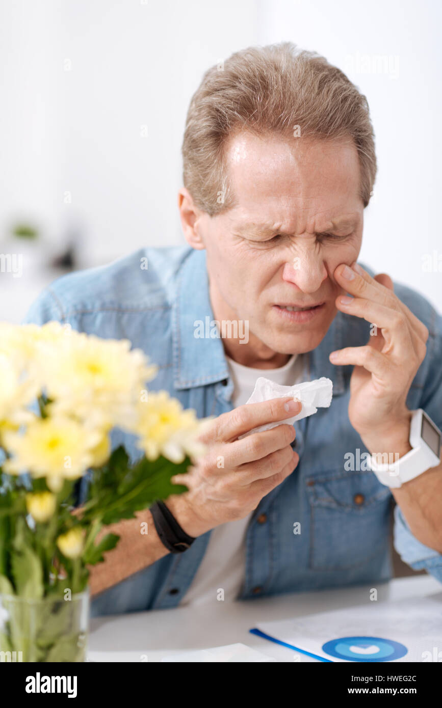 Disturbed man having allergy on flowers Stock Photo - Alamy