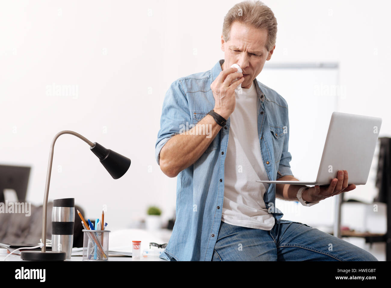 Sick worker holding laptop in left hand Stock Photo - Alamy