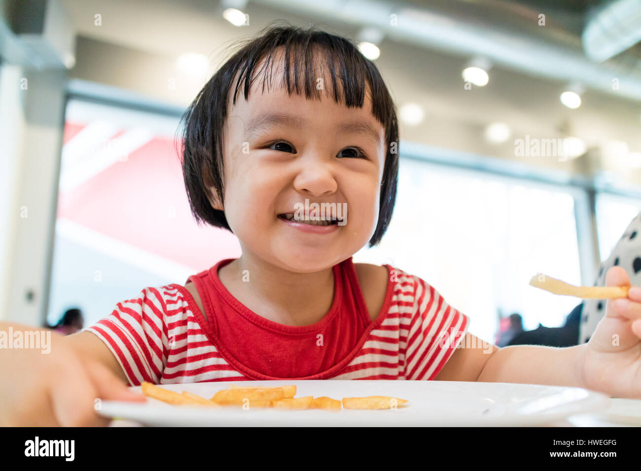 Asian Chinese little girl eating french fries at restaurant Stock Photo ...
