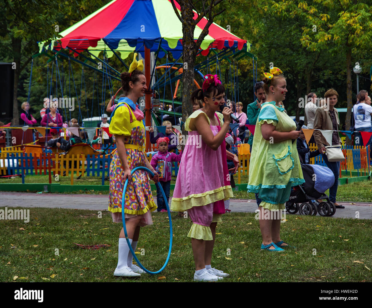 On the green grass in the park are three women dressed in clown ...