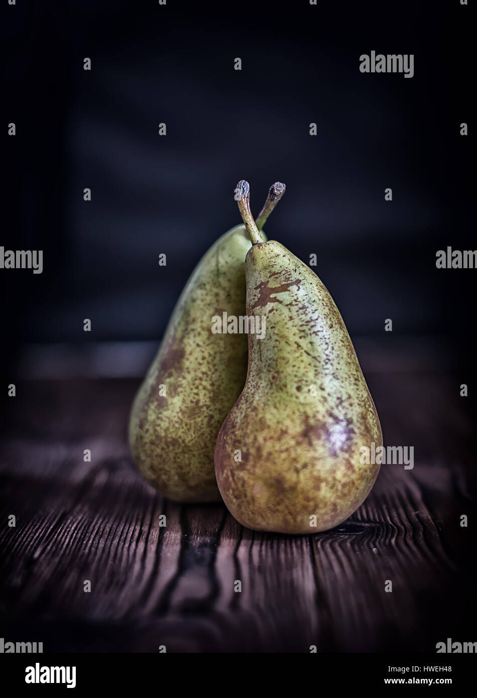 couple pears on old rustic wooden table background, dark toned style ...
