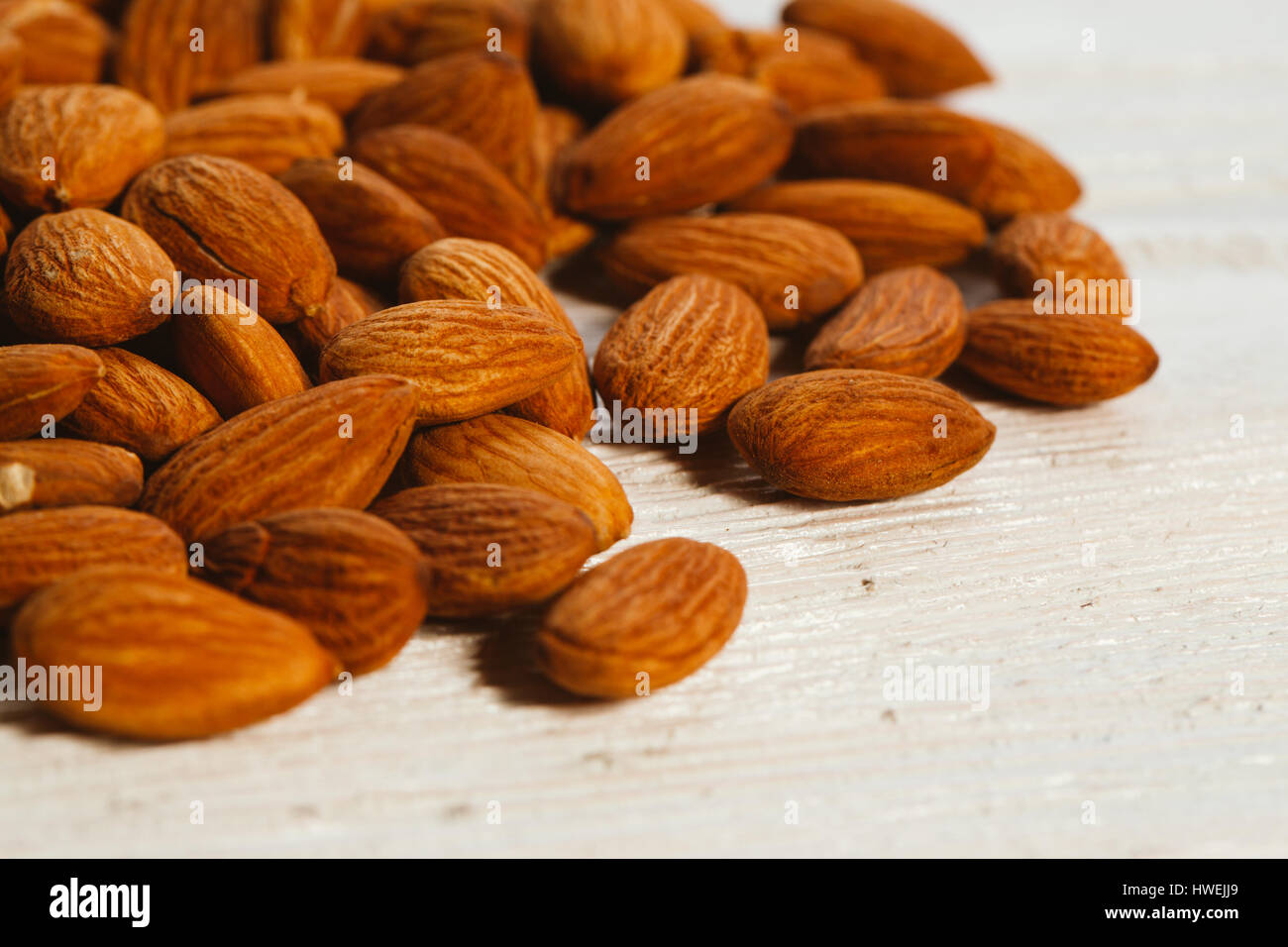handful of almonds on a white wooden background Stock Photo - Alamy