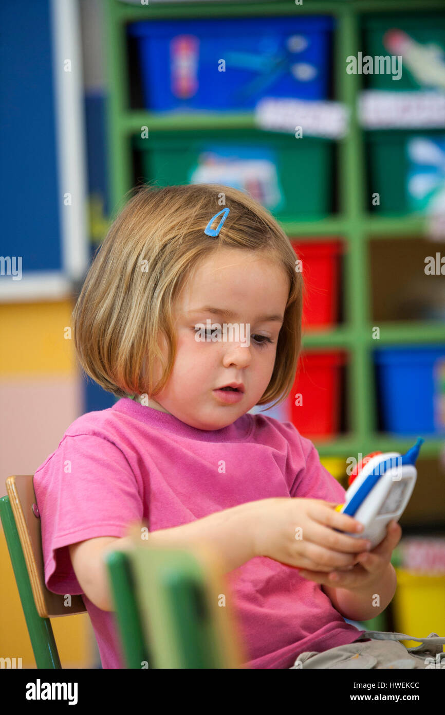 Preschool girl pressing toy cellphone buttons in classroom Stock Photo ...