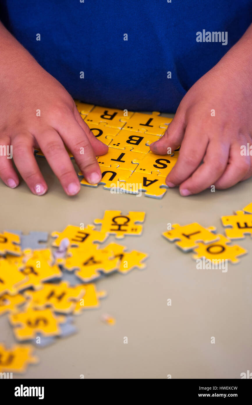 Hands of preschool boy doing jigsaw alphabet in classroom Stock Photo ...